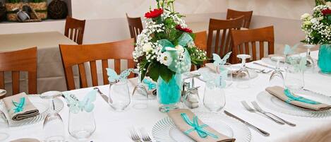 Mesa posta com copos, talheres e um arranjo central com flores e uma etiqueta com nome.