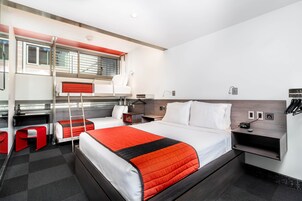 Quarto de hotel moderno com uma cama grande, uma escrivaninha e uma cama beliche.