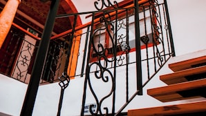 Um edifício com vários andares, apresentando uma escadaria com grades de metal elaboradas e degraus de madeira.