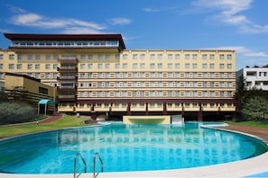 Um hotel com piscina, vários andares e telhado plano.
