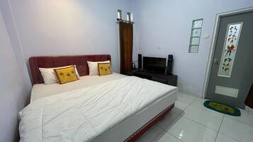 Quarto com uma cama grande, televisão e porta com painéis de vidro decorativos.