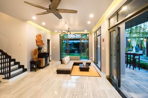 Uma sala de estar moderna com sofá, mesa de centro e ventoinha no teto.