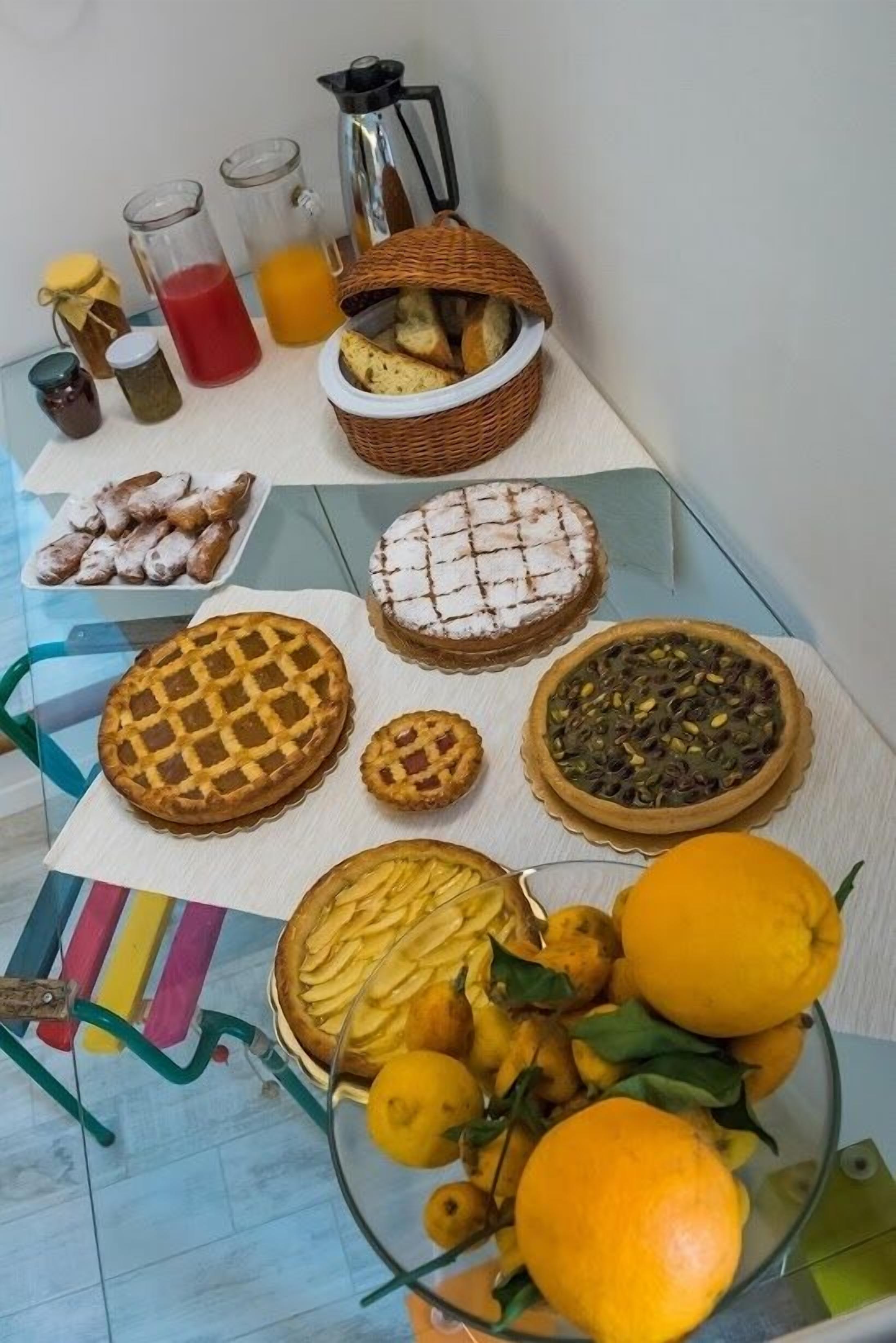 Uma mesa com diversos doces, uma cesta de pão e uma tigela de laranjas.