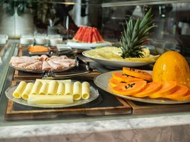 Buffet com diversos alimentos, incluindo carnes, frutas e pães.