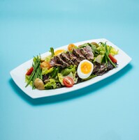Prato branco retangular com salada de alface, tomate cereja, vagem e carne fatiada, acompanhado de um ovo cozido ao meio.