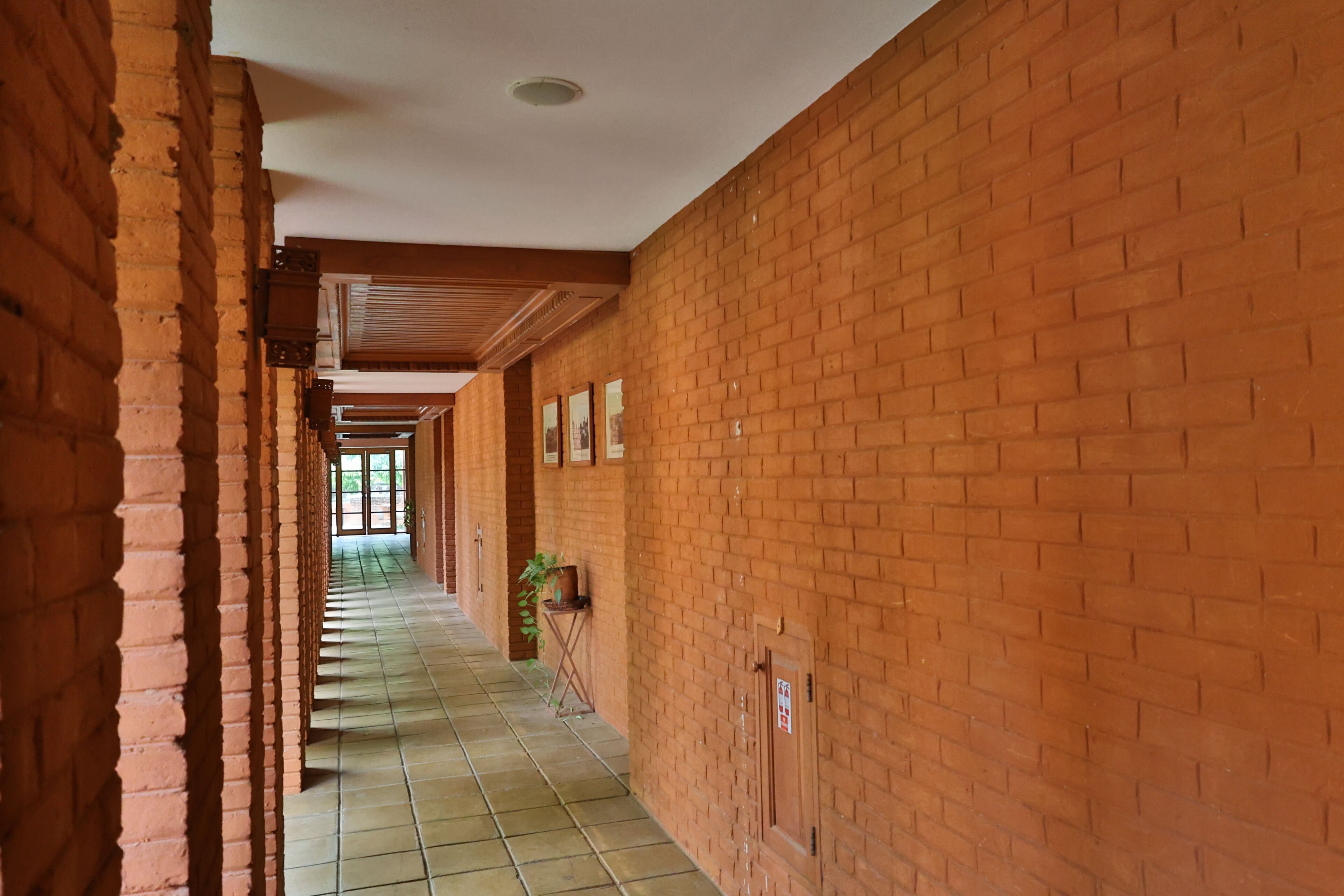 Um corredor com paredes de tijolo, piso de azulejos e teto com iluminação embutida.