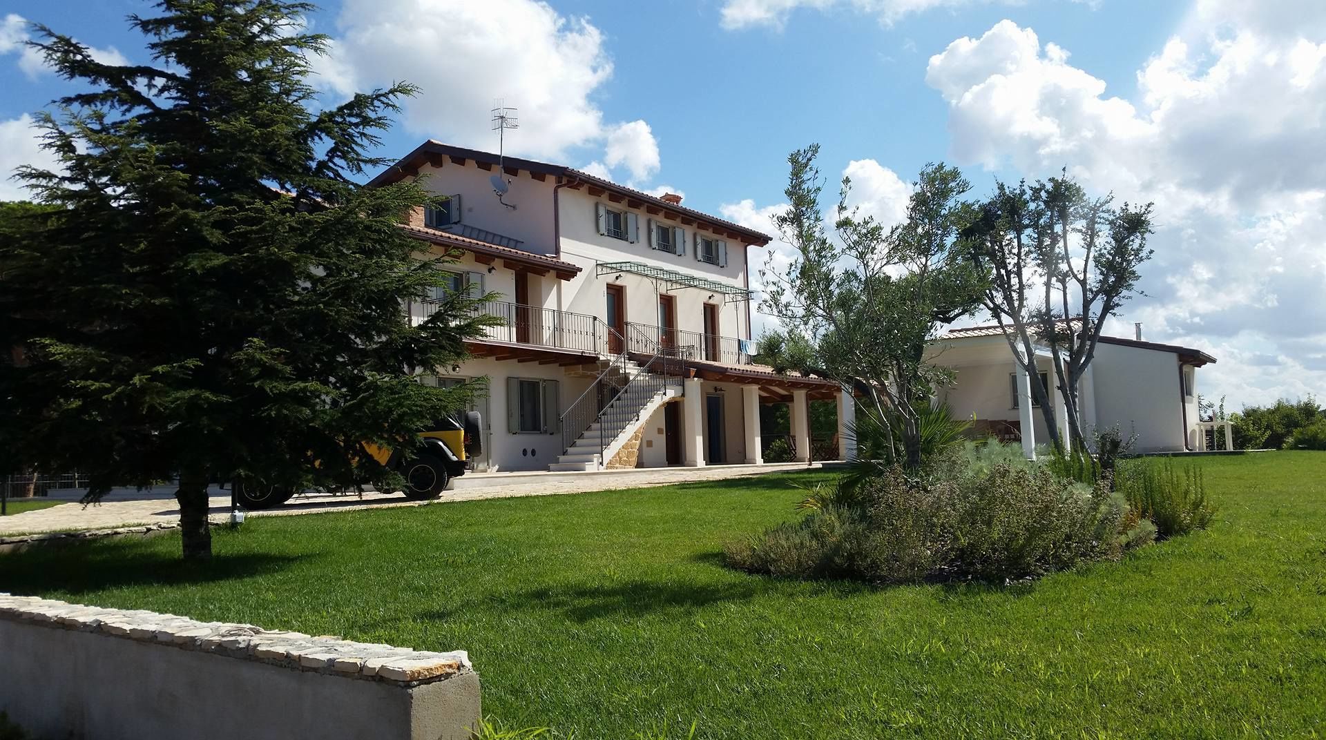 Uma casa de dois andares com varanda, entrada para carros e gramado.