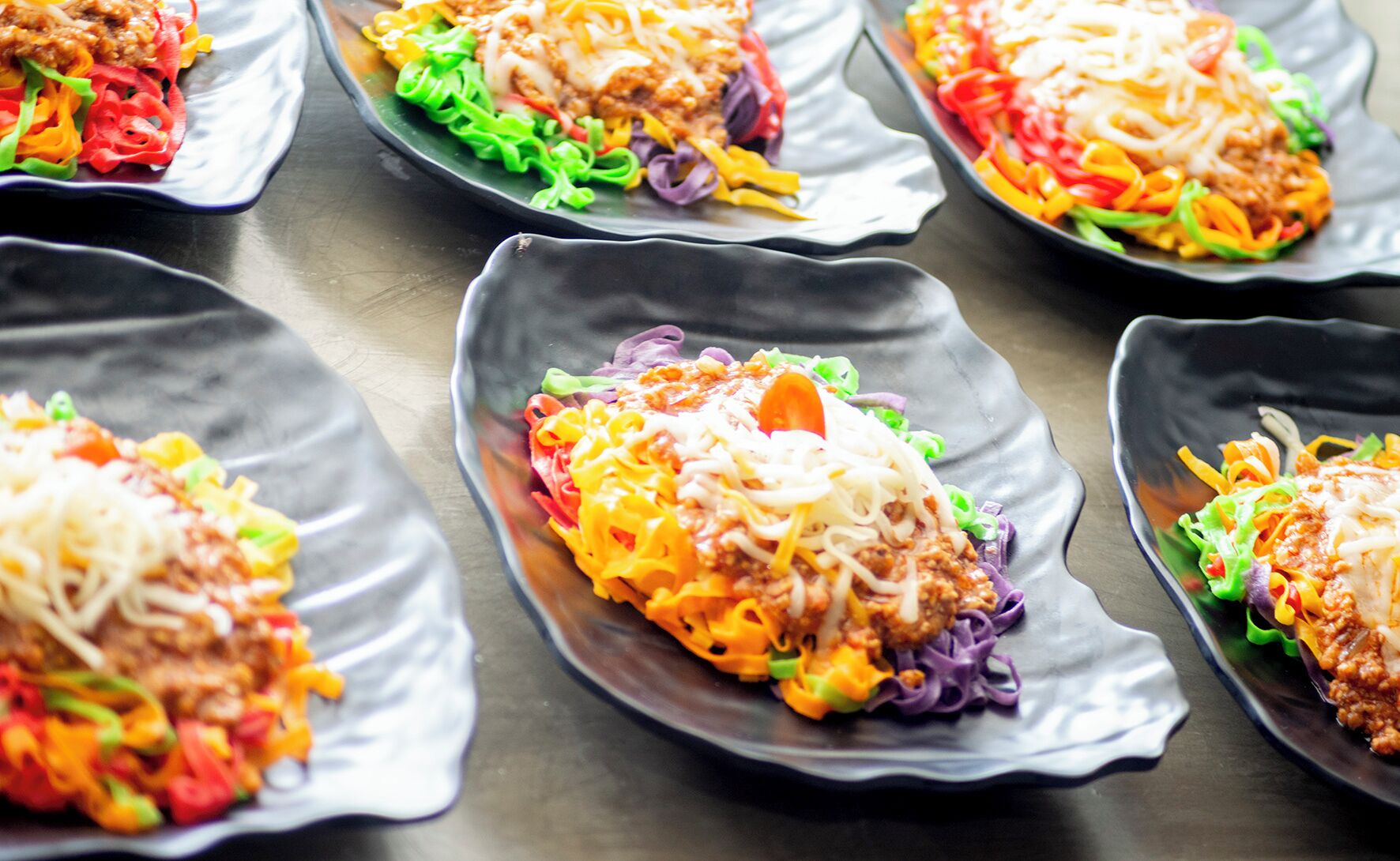 Uma mesa com vários pratos de coloridos pratos de macarrão.