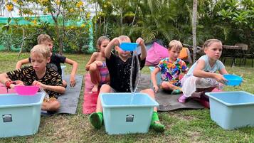 Crianças brincando com recipientes de água ao ar livre.