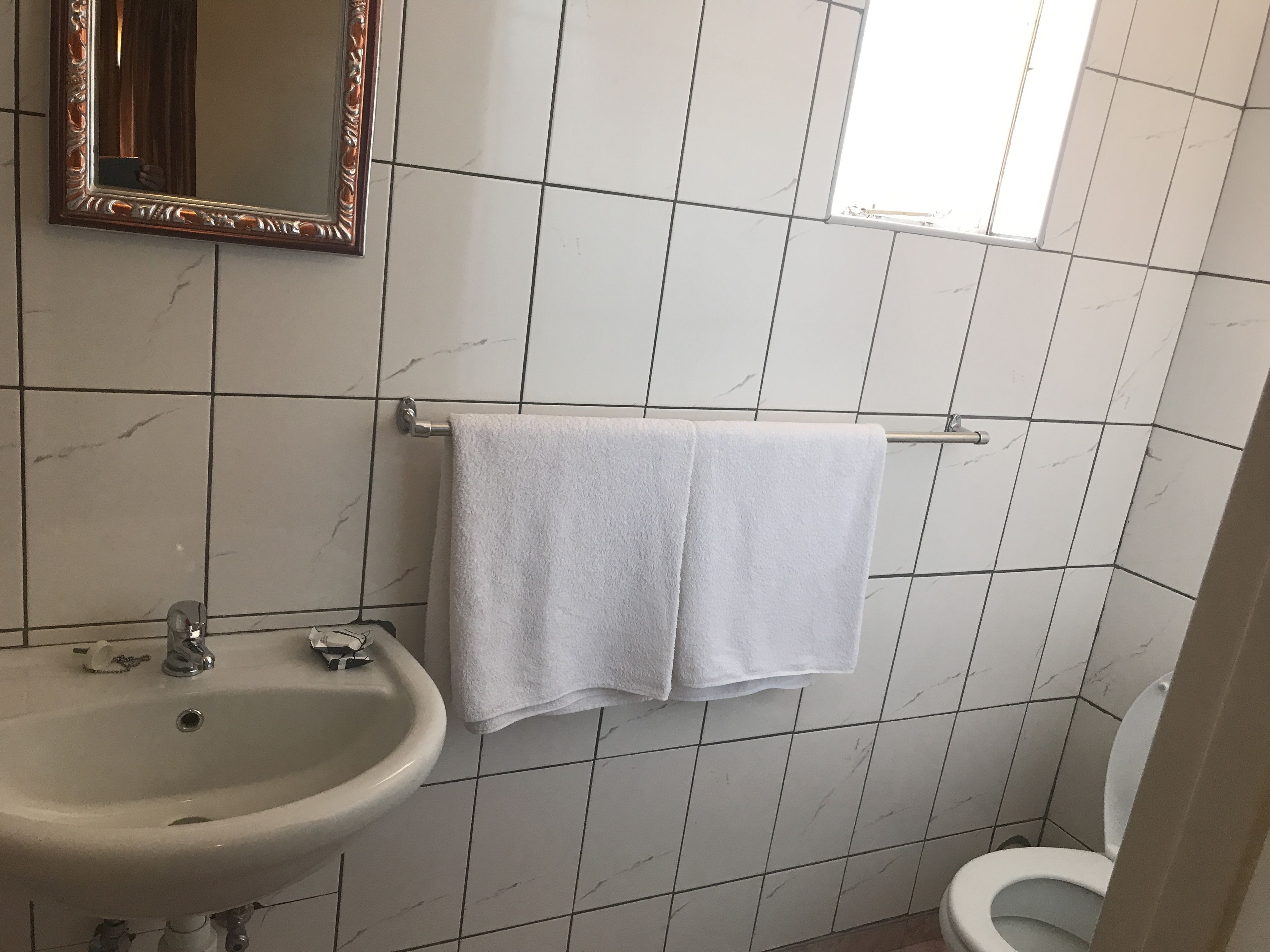 Casa de banho com lavatório, espelho e porta-toalhas.