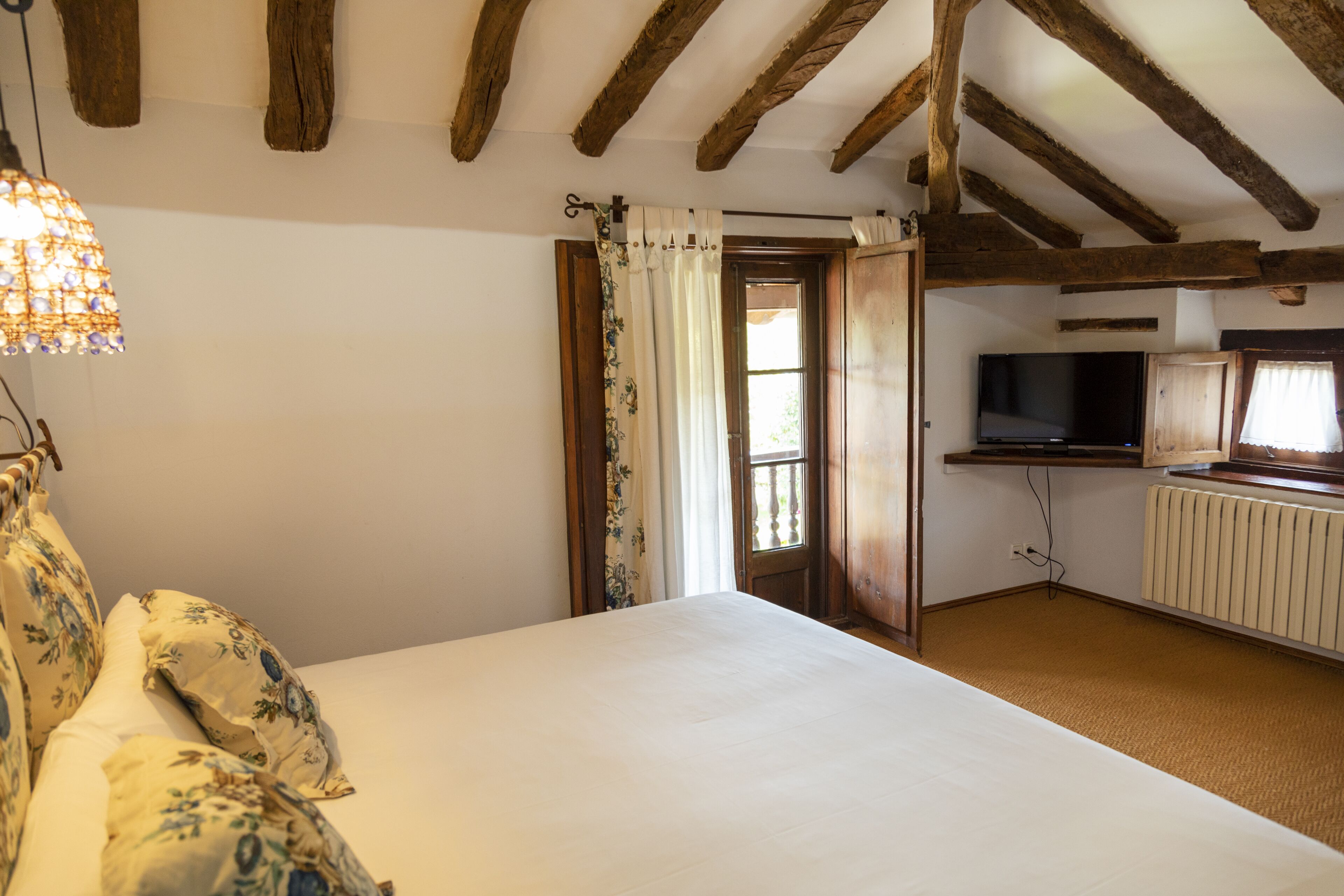 Quarto com cama, televisão e janela com cortinas.