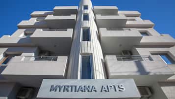Um edifício moderno com um elemento vertical central e várias varandas.