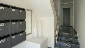Um interior moderno com escada, armários escuros e vasos brancos sobre um pedestal.
