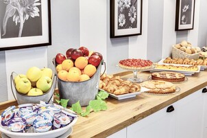 Mesa de buffet com frutas, pastelaria e iogurte.