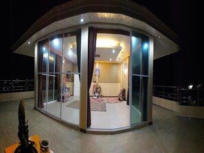 Um quarto moderno com paredes de vidro, teto curvo, tapete central e televisão.