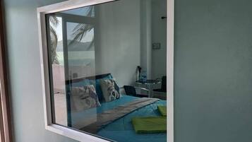 Quarto com cama, almofadas, mesa pequena e cadeira.