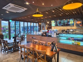 Interior de café com móveis de madeira, balcão com máquina de café e um quadro de cardápio.