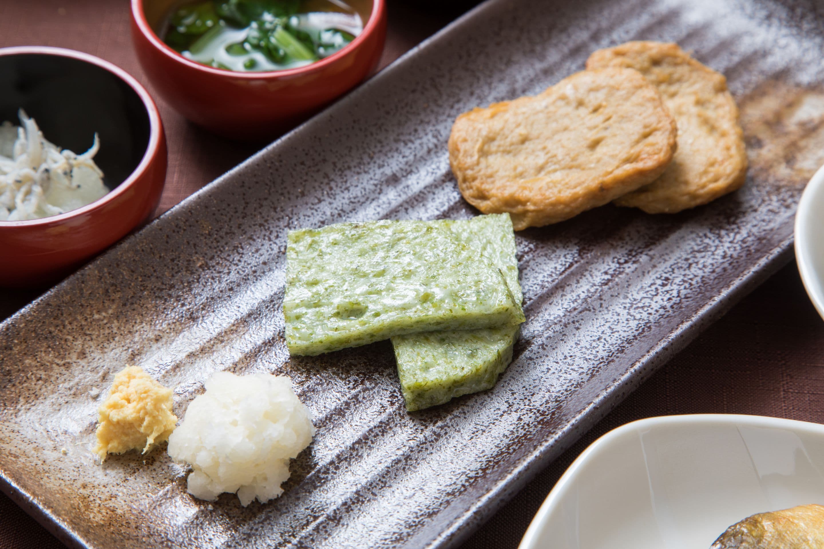Um prato retangular com matcha verde, arroz branco e dois biscoitos.