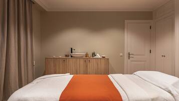 Quarto de hotel com uma cama, cómoda de madeira, pia e porta.