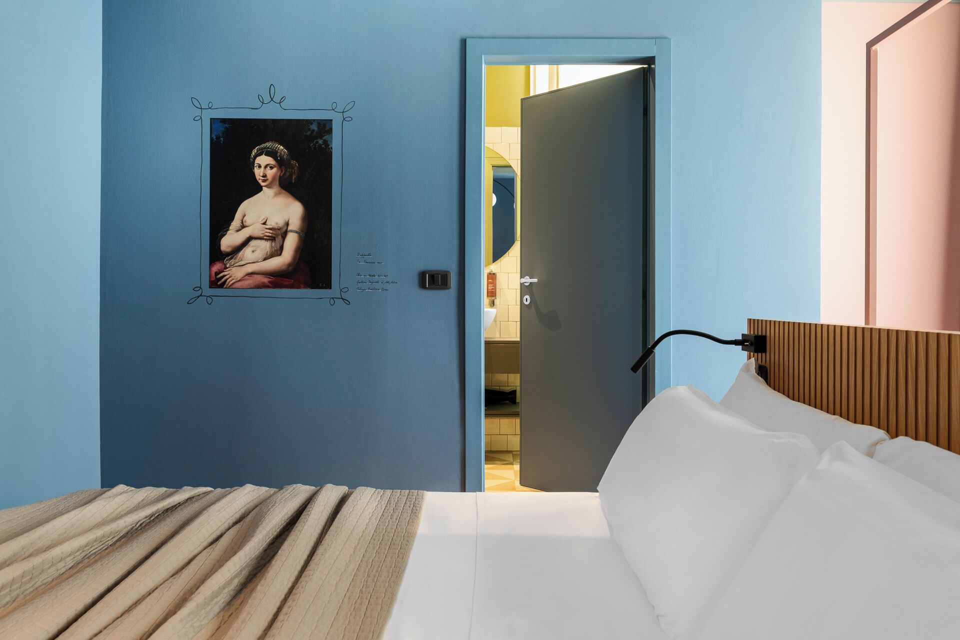 Quarto com uma cama, uma porta para um banheiro e um quadro na parede.