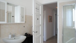 Uma casa de banho com lavatório, espelho e chuveiro.