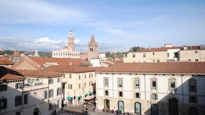 Uma praça histórica na cidade com arquitetura tradicional, incluindo um campanário e uma igreja.