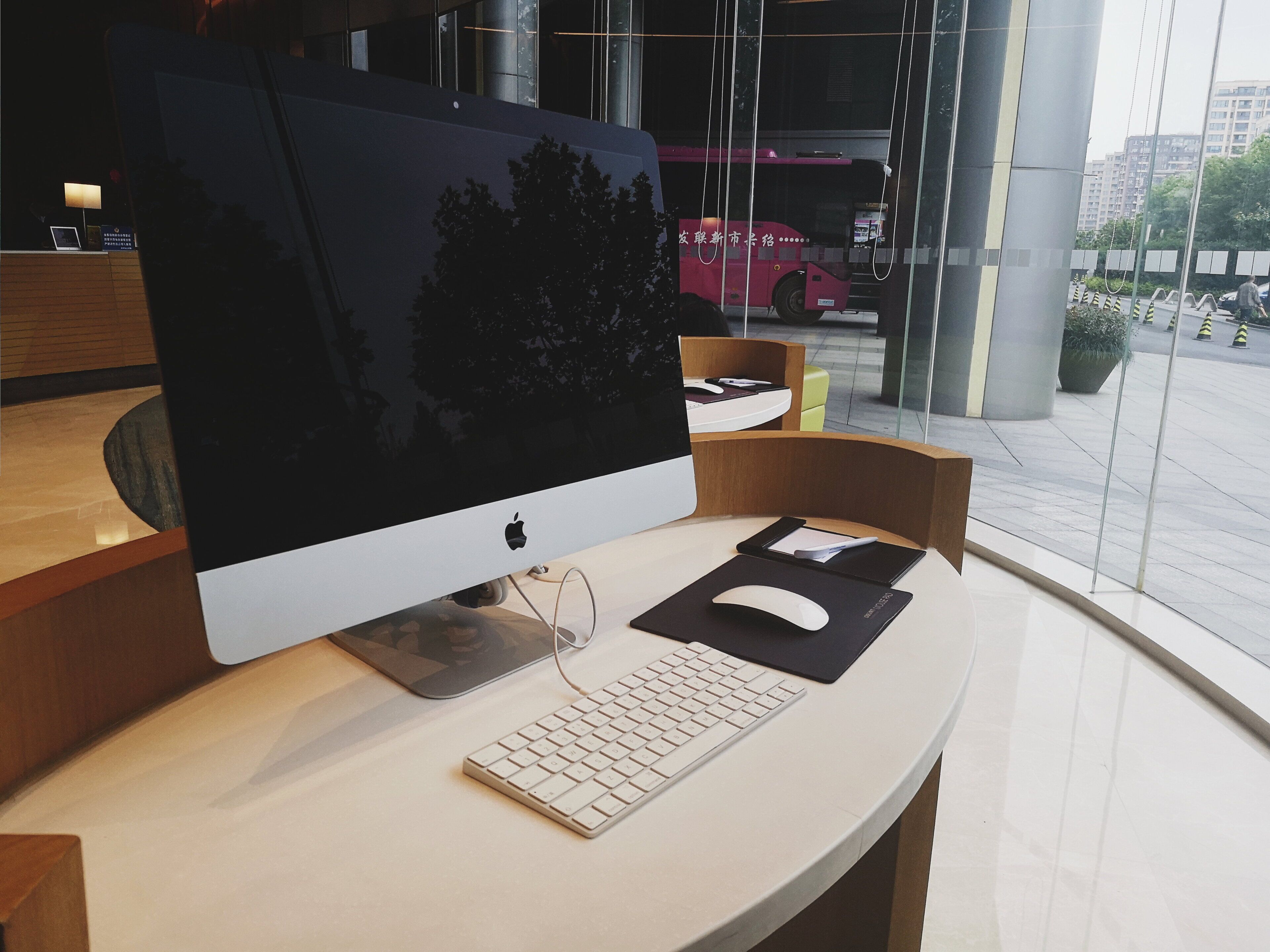 Um espaço de trabalho moderno com um computador de mesa, teclado e rato numa mesa curva.