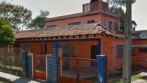 Um edifício de dois andares com fachada vermelha, telhado ladrilhado e portão fechado.