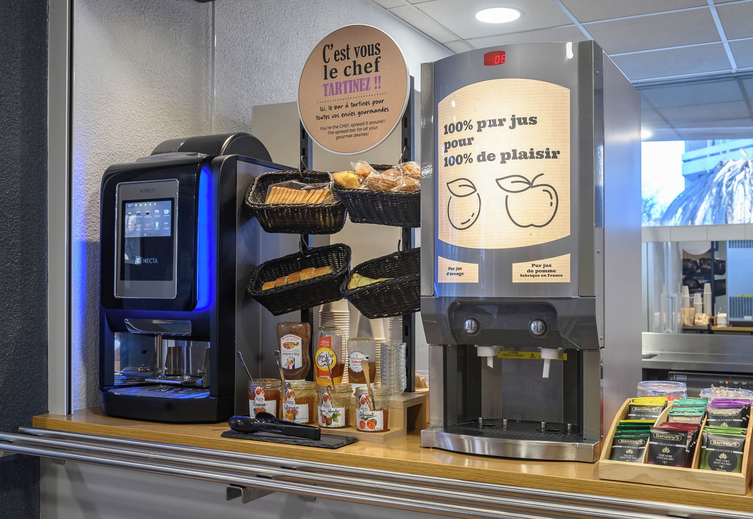 Uma máquina de café, uma placa com texto em francês e cestos de doces.