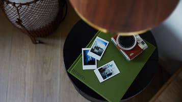 Uma mesa redonda com superfície verde, um livro intitulado 'Phaidon' e duas fotografias.