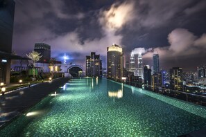 Uma piscina infinita no terraço com vista para o horizonte da cidade, incluindo uma torre imponente.