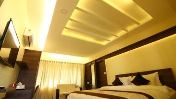 Quarto de hotel com cama, televisão, escrivaninha e cadeira.