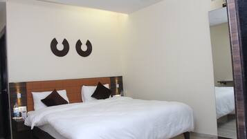 Quarto de hotel com uma cama grande, cabeceira de madeira, duas luminárias na parede e um espelho.