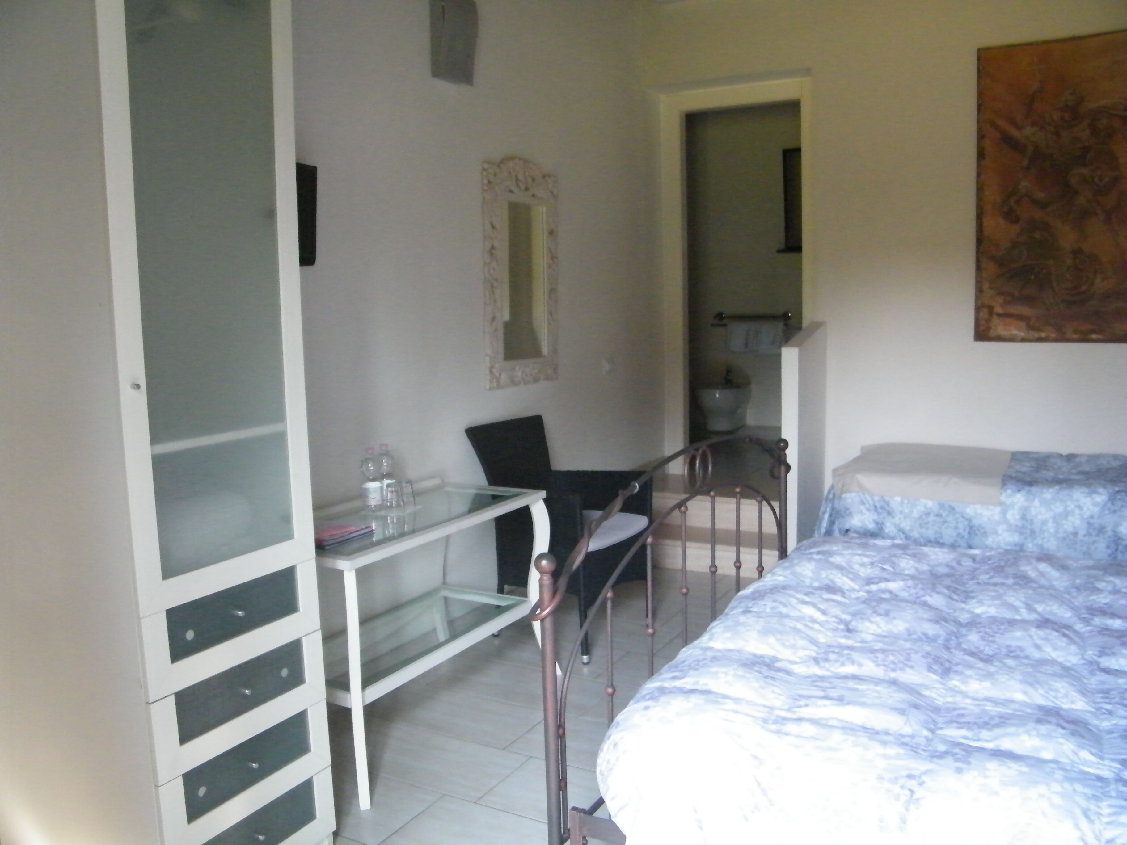 Um quarto com cama, escrivaninha, cadeira e guarda-roupa.