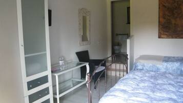 Um quarto com cama, escrivaninha, cadeira e guarda-roupa.