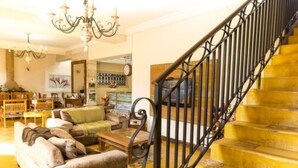 Uma sala de estar espaçosa com escada, um candelabro e um espaço para refeições.