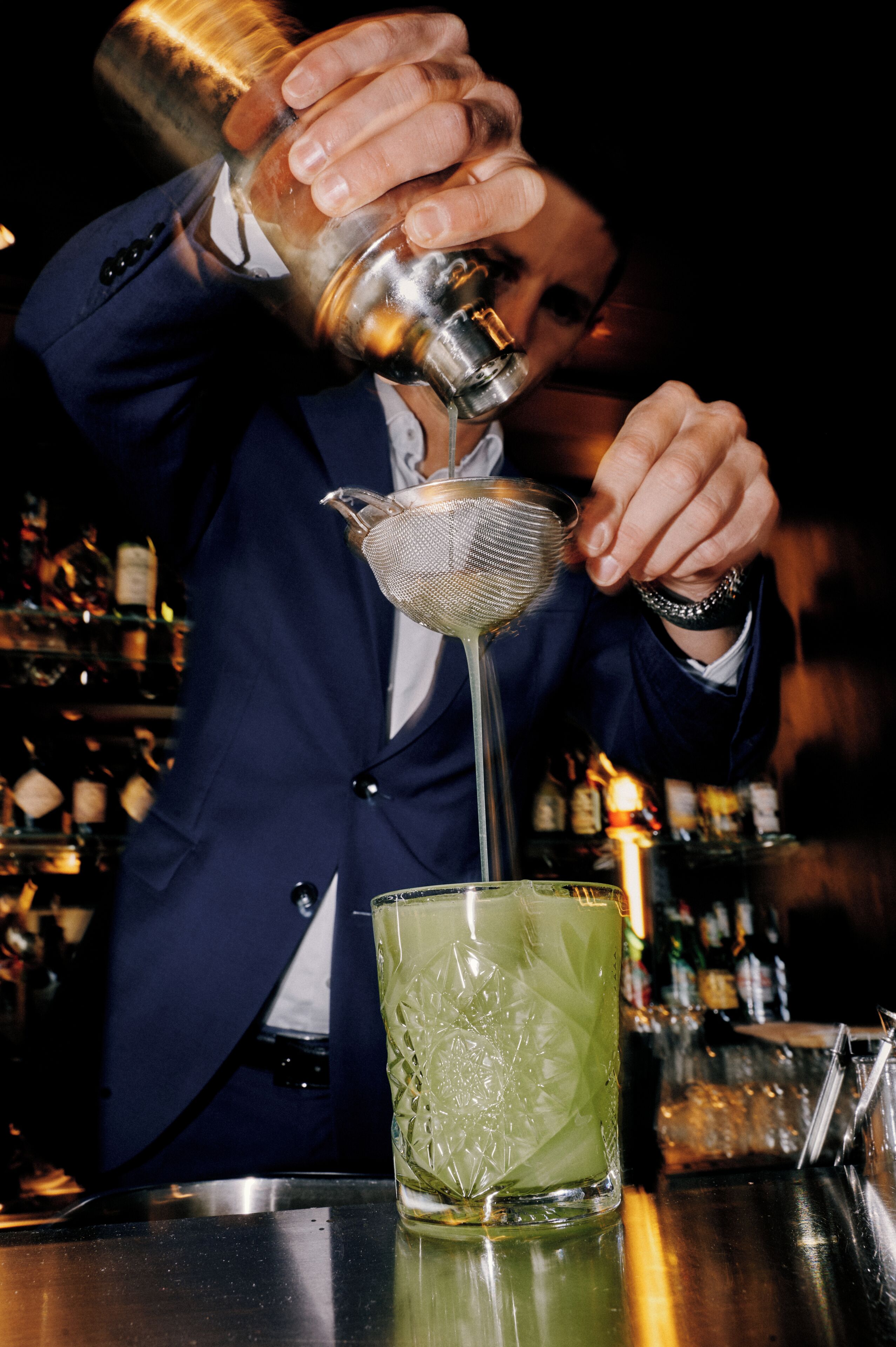 Um bartender servindo uma bebida num copo.