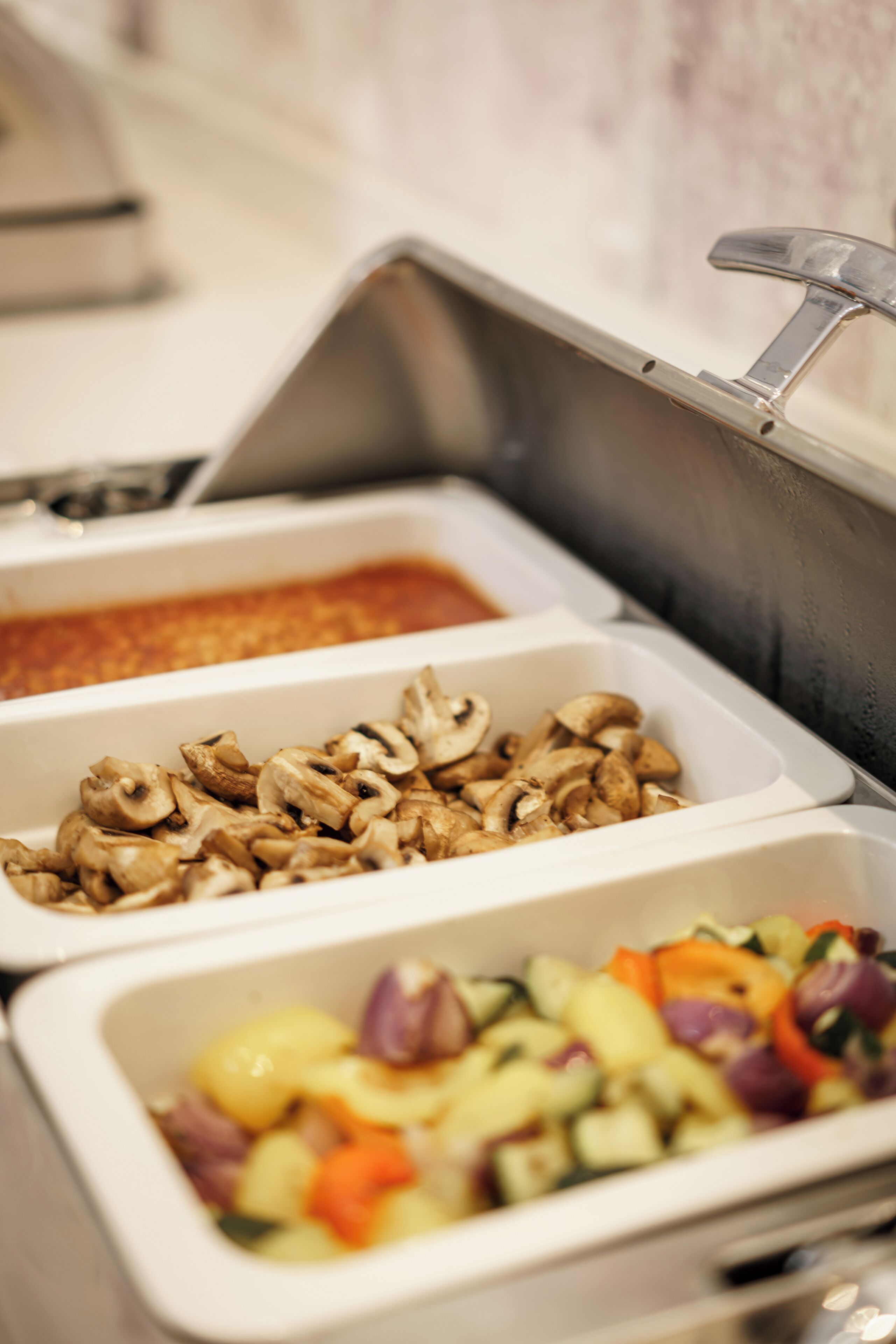 Buffet com diversas opções de comida, incluindo cogumelos e uma mistura de legumes.