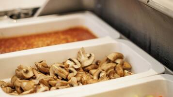 Buffet com diversas opções de comida, incluindo cogumelos e uma mistura de legumes.