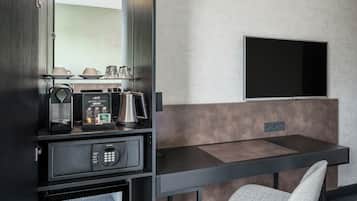 Quarto de hotel moderno com cozinha compacta, televisão de tela plana e piso estampado.