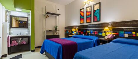 Quarto de hotel com duas camas, banheiro e ventilador de teto.