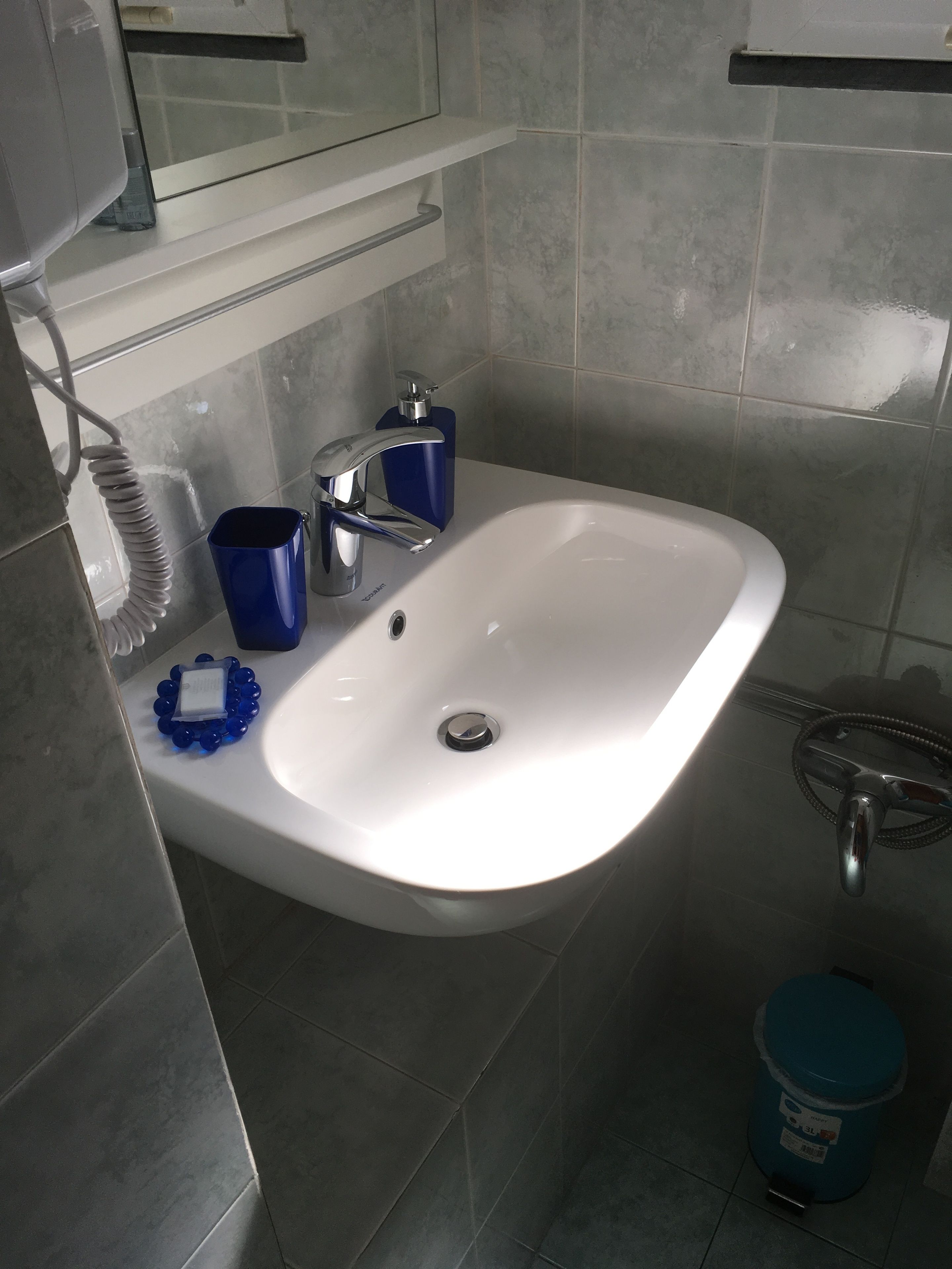 Casa de banho com lavatório branco, dispensador de sabonete azul e suporte de sabonete azul.