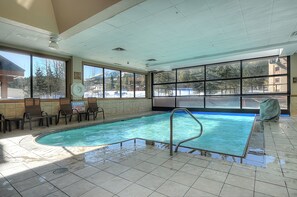 Piscina interior com vista desobstruída para o exterior, cadeira de salva-vidas e aviso.