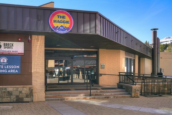 Um edifício com uma placa indicando 'The Maggie Bar & Restaurant' e uma placa 'Breck Sports Snowboard Shop'.