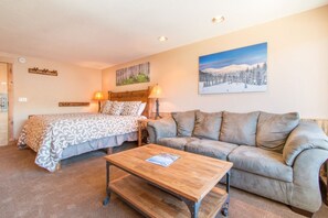 Quarto com cama, sofá e mesa de centro de madeira.