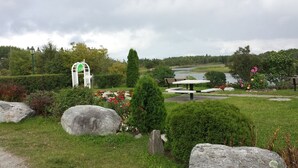 Um parque com um coreto, mesas para piquenique e um lago.