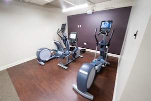 Uma sala de ginástica com três bicicletas ergométricas e uma esteira.