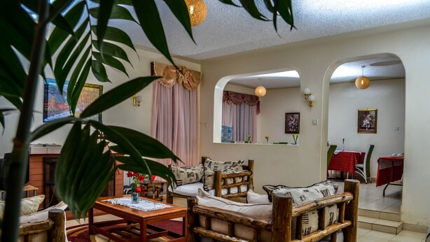 Uma sala de estar aconchegante com um sofá de madeira, uma mesa de centro e um espaço de jantar com toalha quadriculada vermelha e branca.