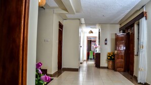 Um corredor com uma porta de madeira à esquerda, outra porta de madeira à direita e uma pequena mesa com flores no centro.
