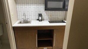 Uma cozinha compacta com pia, cafeteira, micro-ondas e fogão.